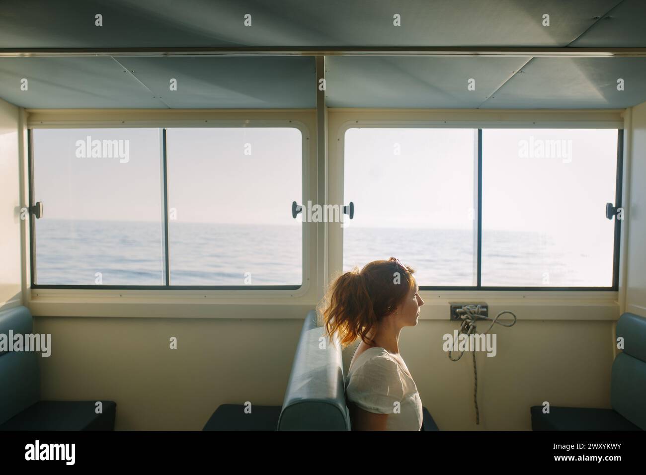 A contemplative woman gazes out the window at the sea from inside a ...