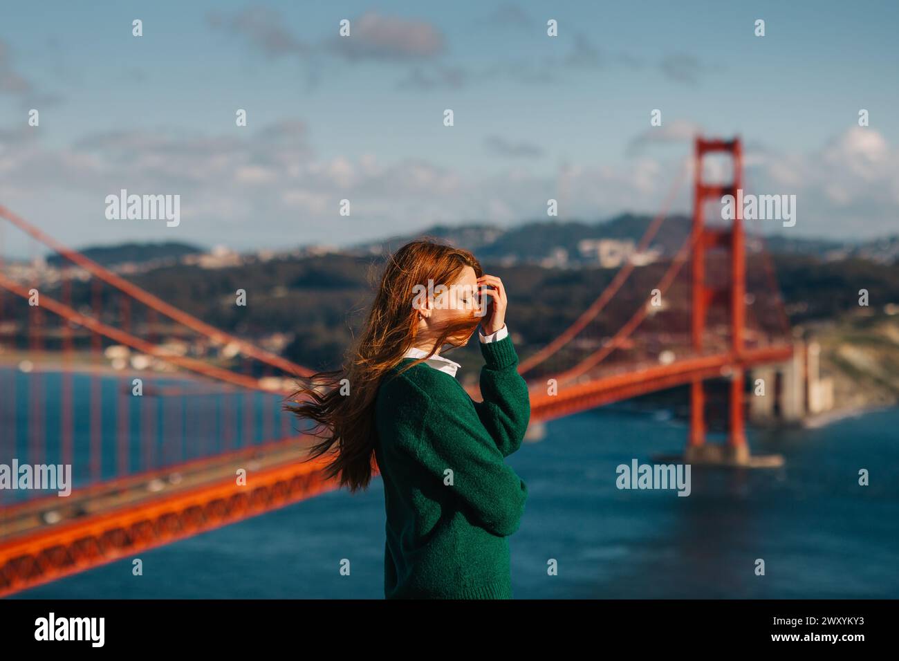 A reflective moment as a woman with wind-tossed hair looks out over the ...