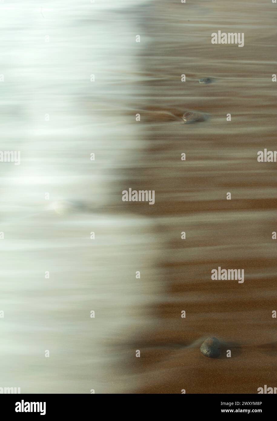 A tranquil scene with smooth water flowing over pebbles and sand at ...