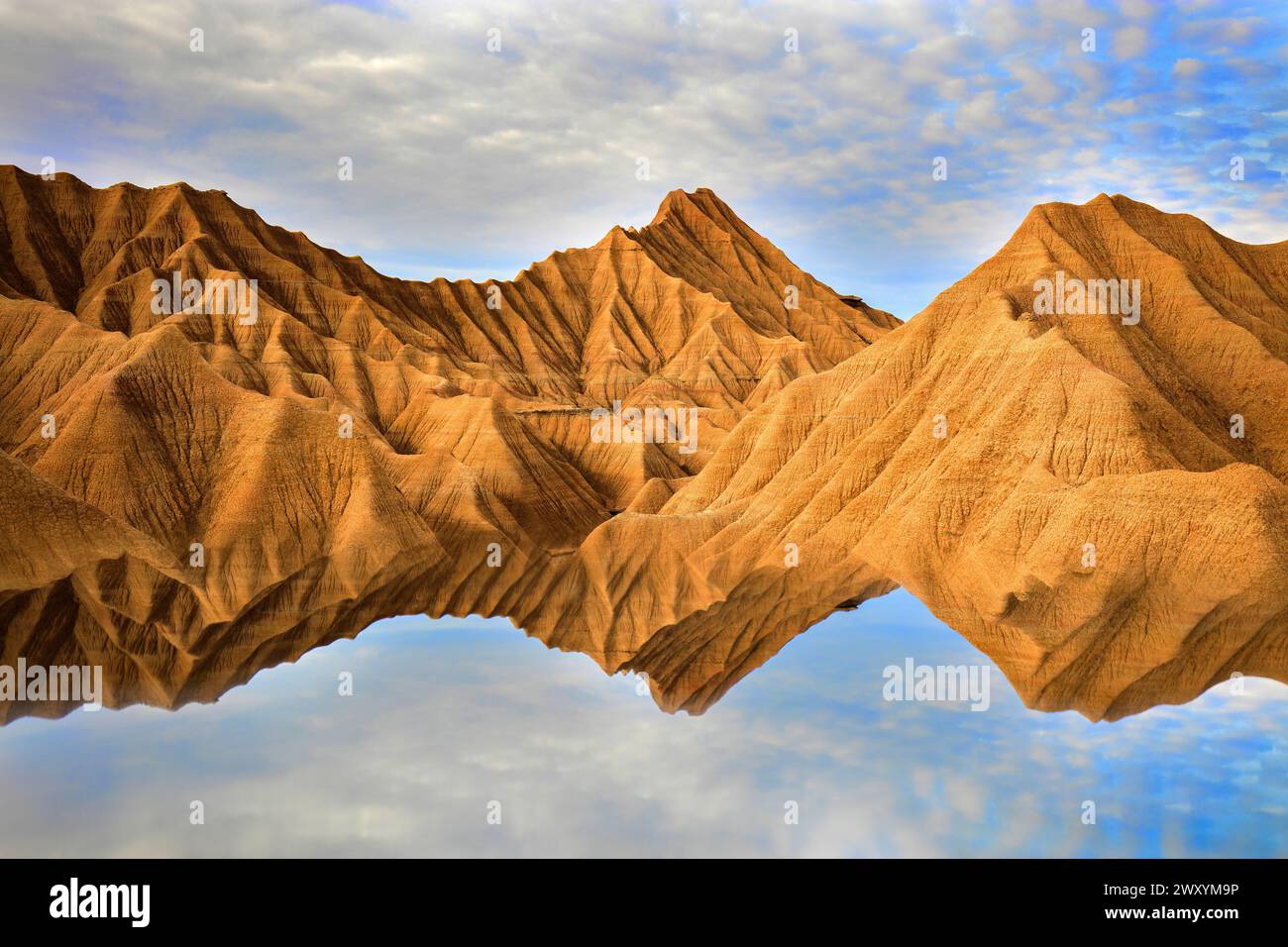 Perfect reflection of the detailed ridges of badlands in still water ...