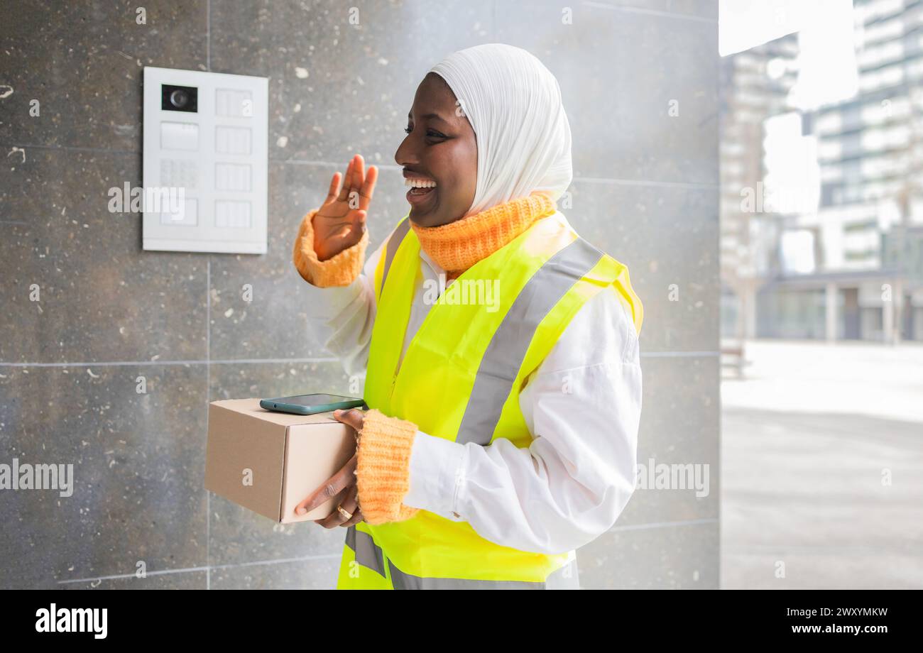 Side view of cheerful Muslim woman in a hijab and high-visibility vest ...