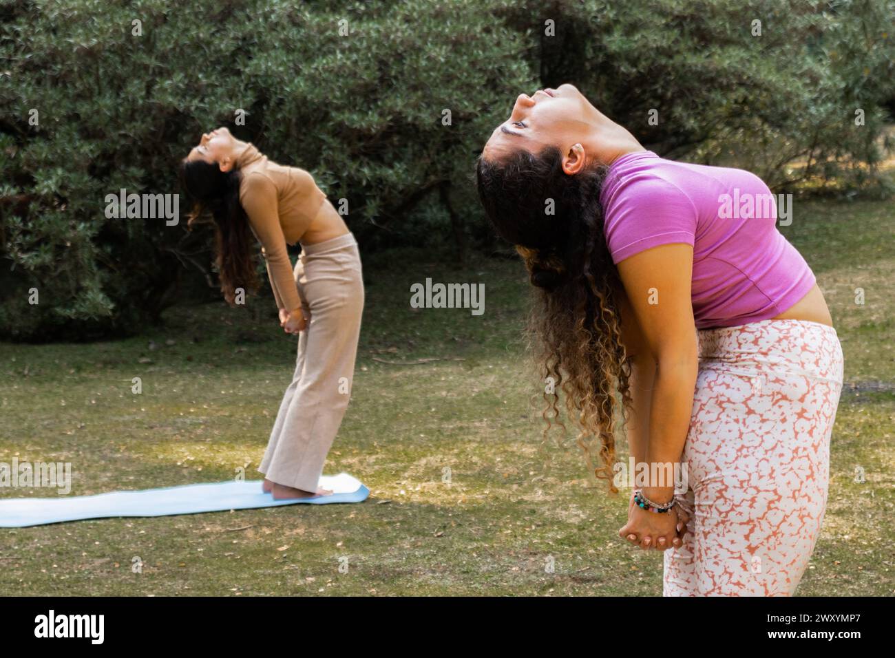 Two women perform synchronized backbend yoga poses, enhancing their ...