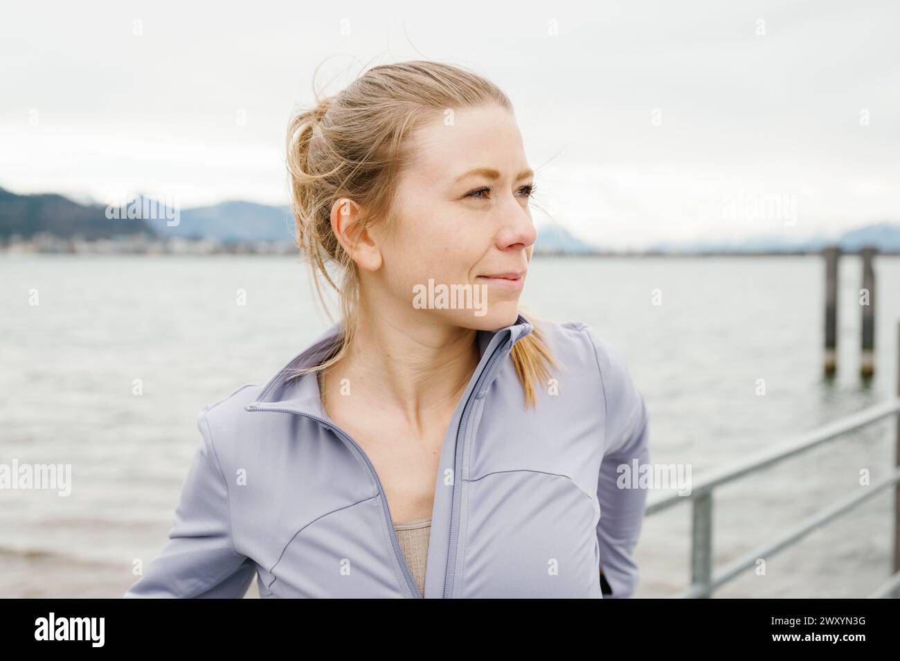 A contemplative woman takes a break from her fitness routine by a ...