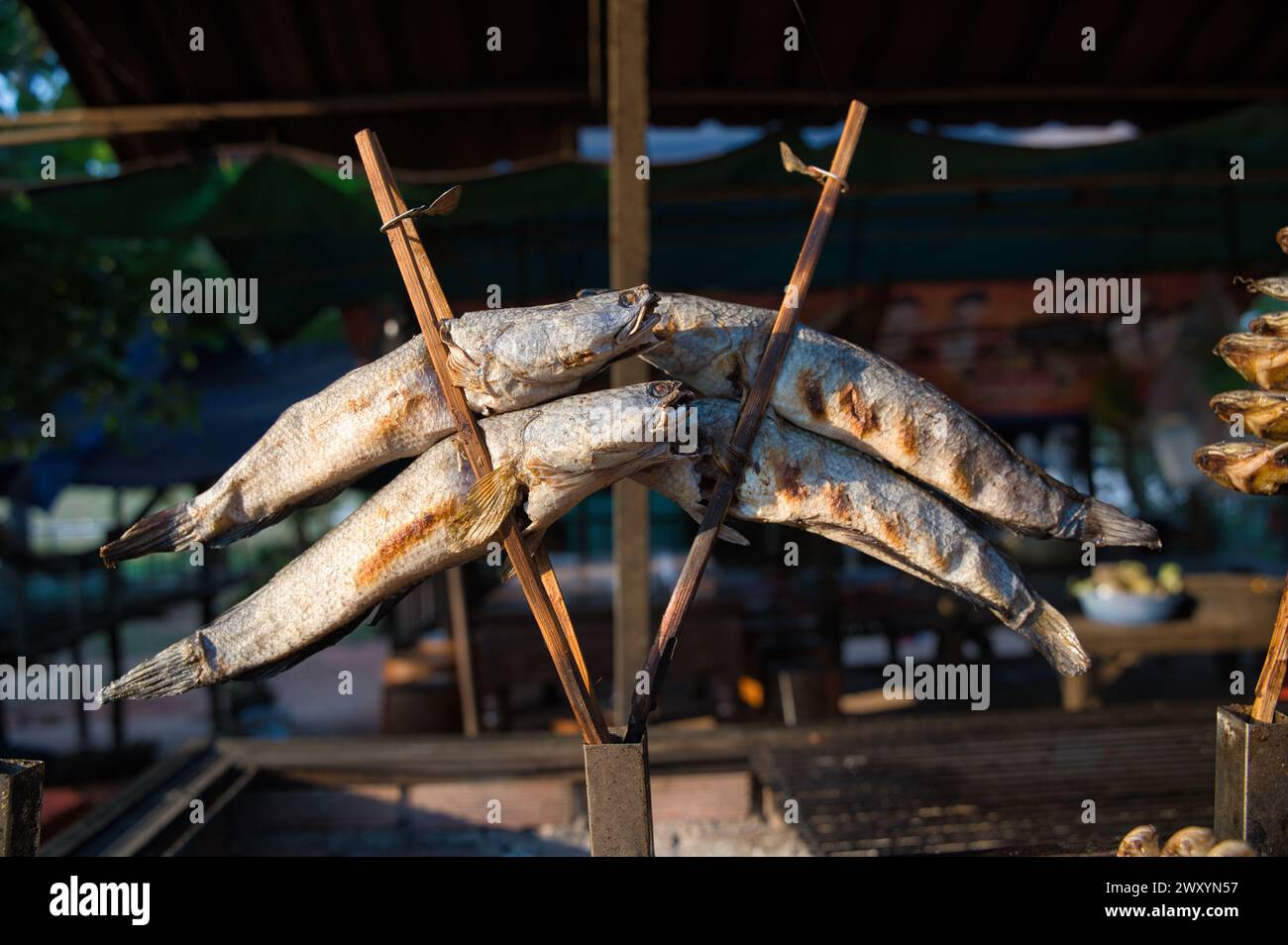 Dried fish on wooden sticks at a traditional outdoor market Stock Photo ...