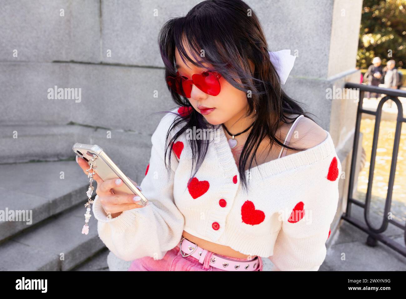A trendy Gen-Z chinese girl wearing heart-shaped sunglasses uses her ...