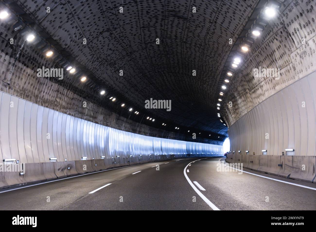 An empty, well-lit modern tunnel featuring a curved roadway and ...