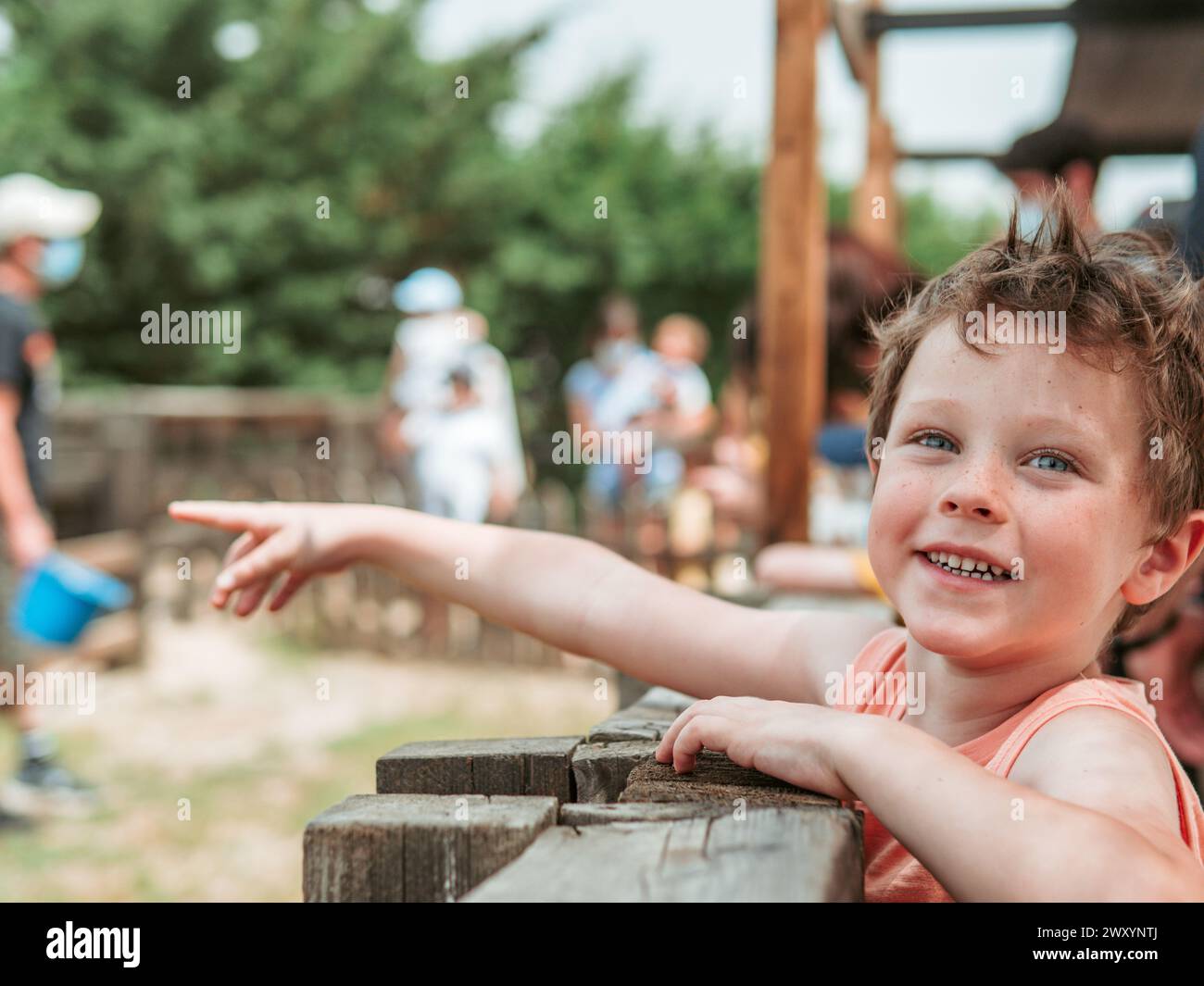 With sparkling eyes and a joyful smile, a young boy points excitedly at ...