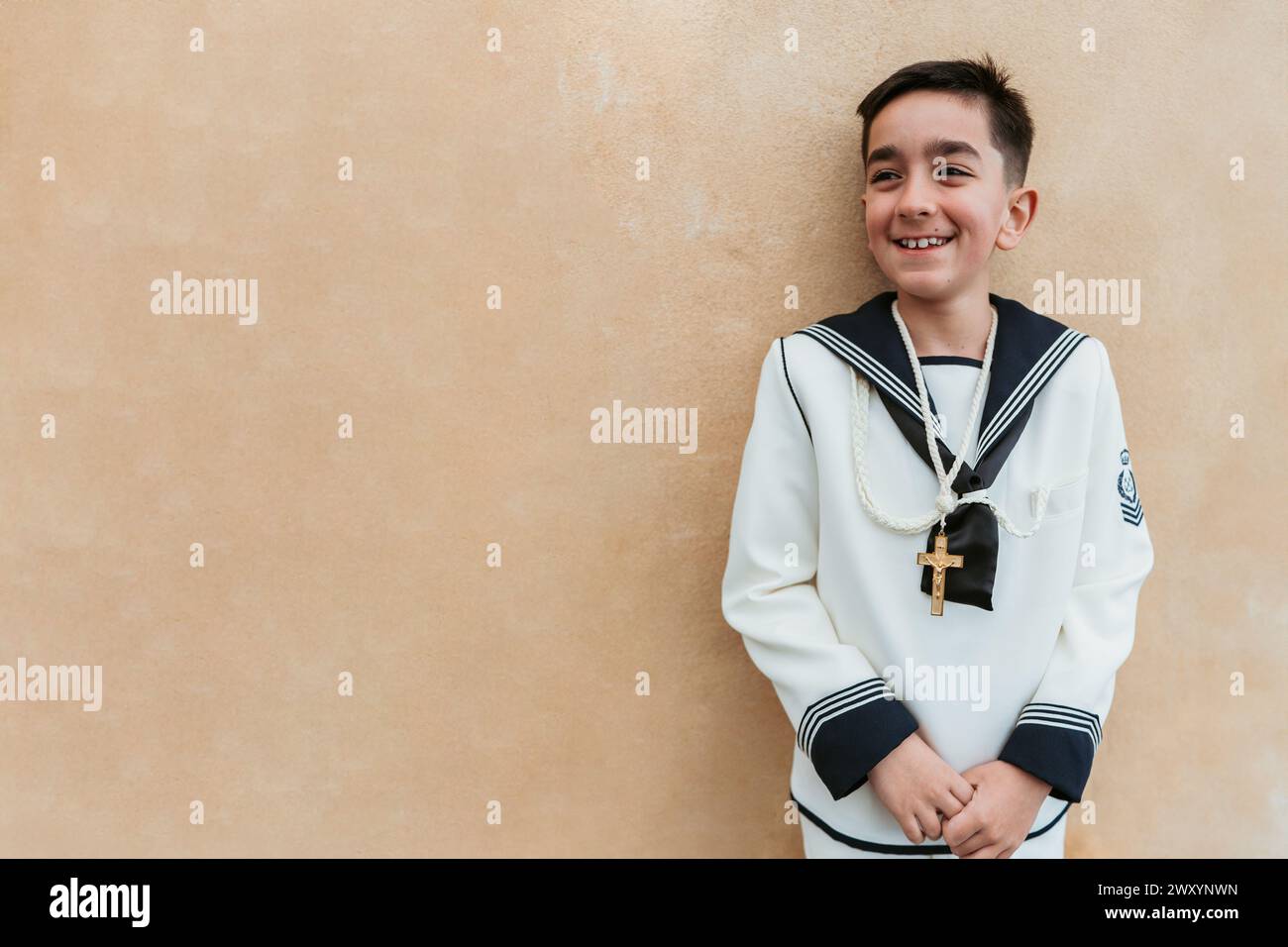 A cheerful boy stands against a simple backdrop, proudly wearing his ...