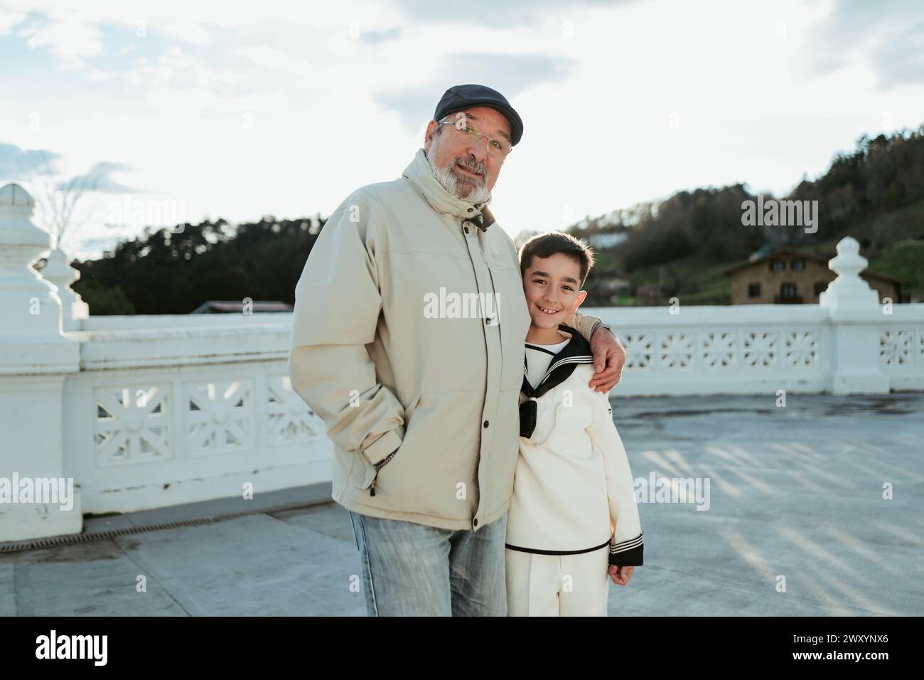 A proud grandfather in a cap embraces his grandson in First Communion ...