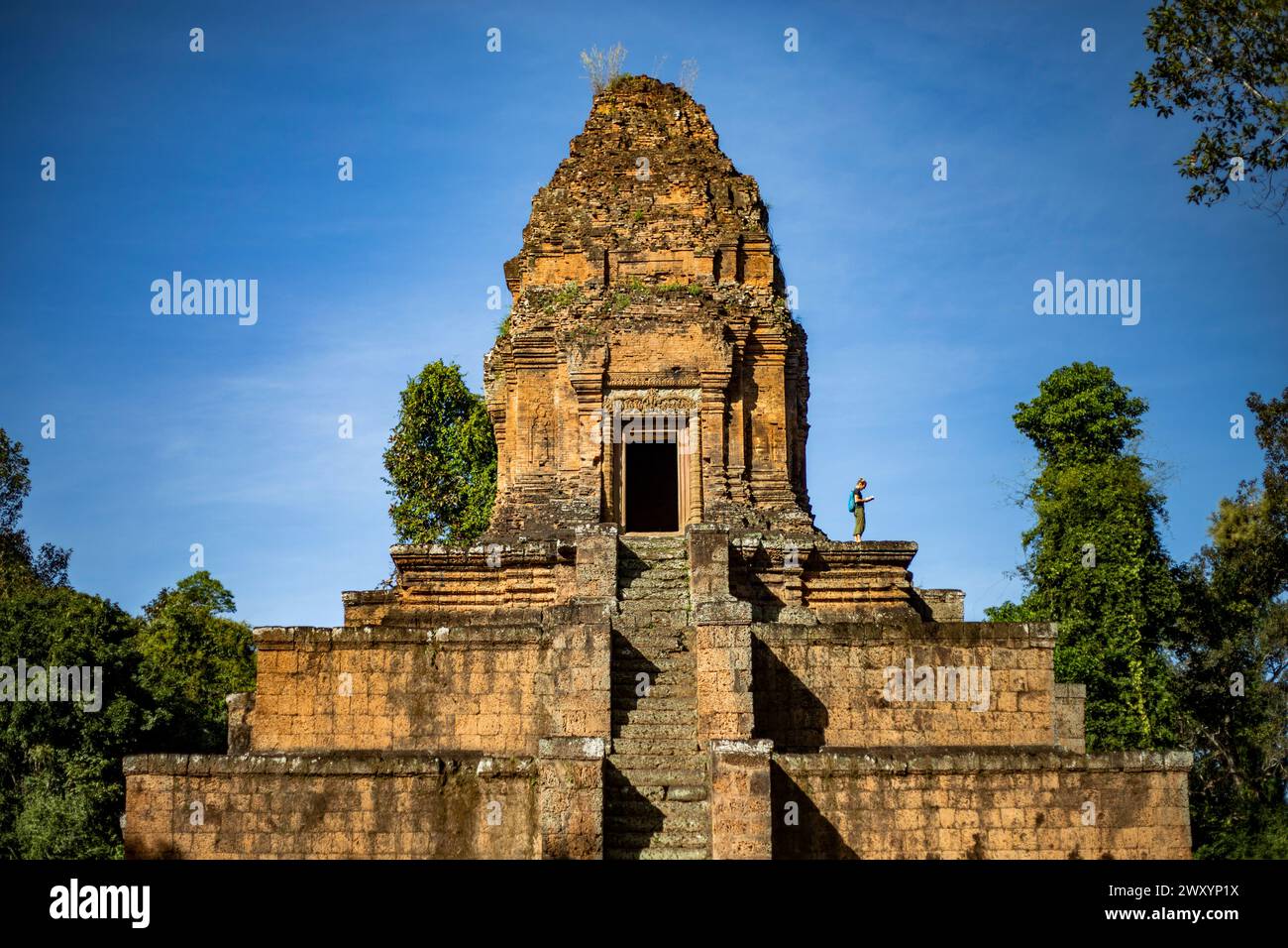 A tourist stands atop the ancient ruins of Angkor Wat, admiring the ...