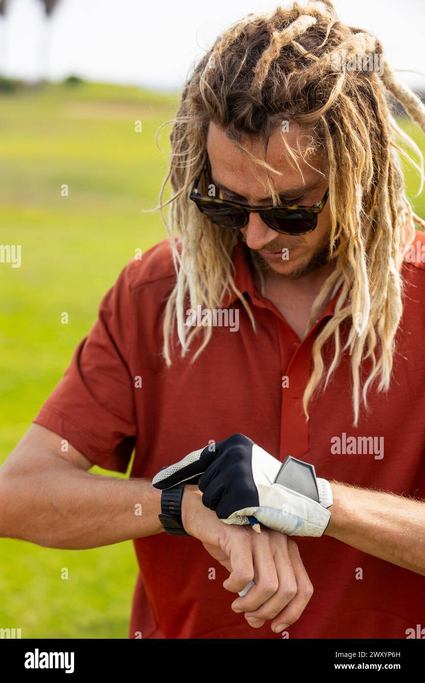 A male golfer with distinctive blonde dreadlocks wears sunglasses and ...