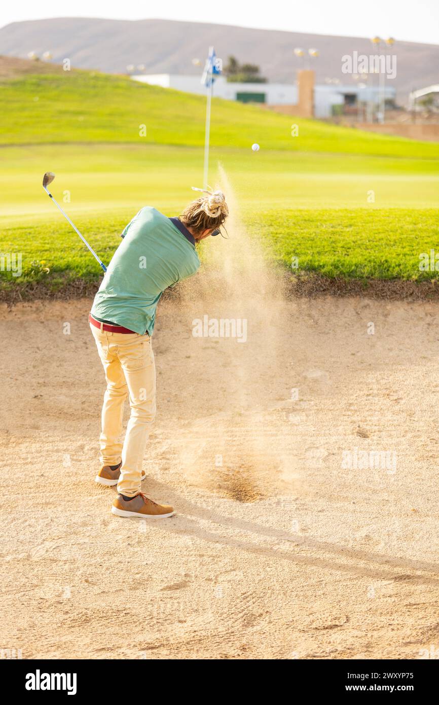 Back view of a golfer with unorthodox dreadlocks hits a ball from a ...