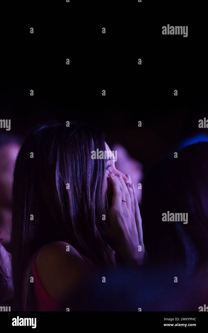 A woman in a crowd at a concert is captured in a profound moment of ...