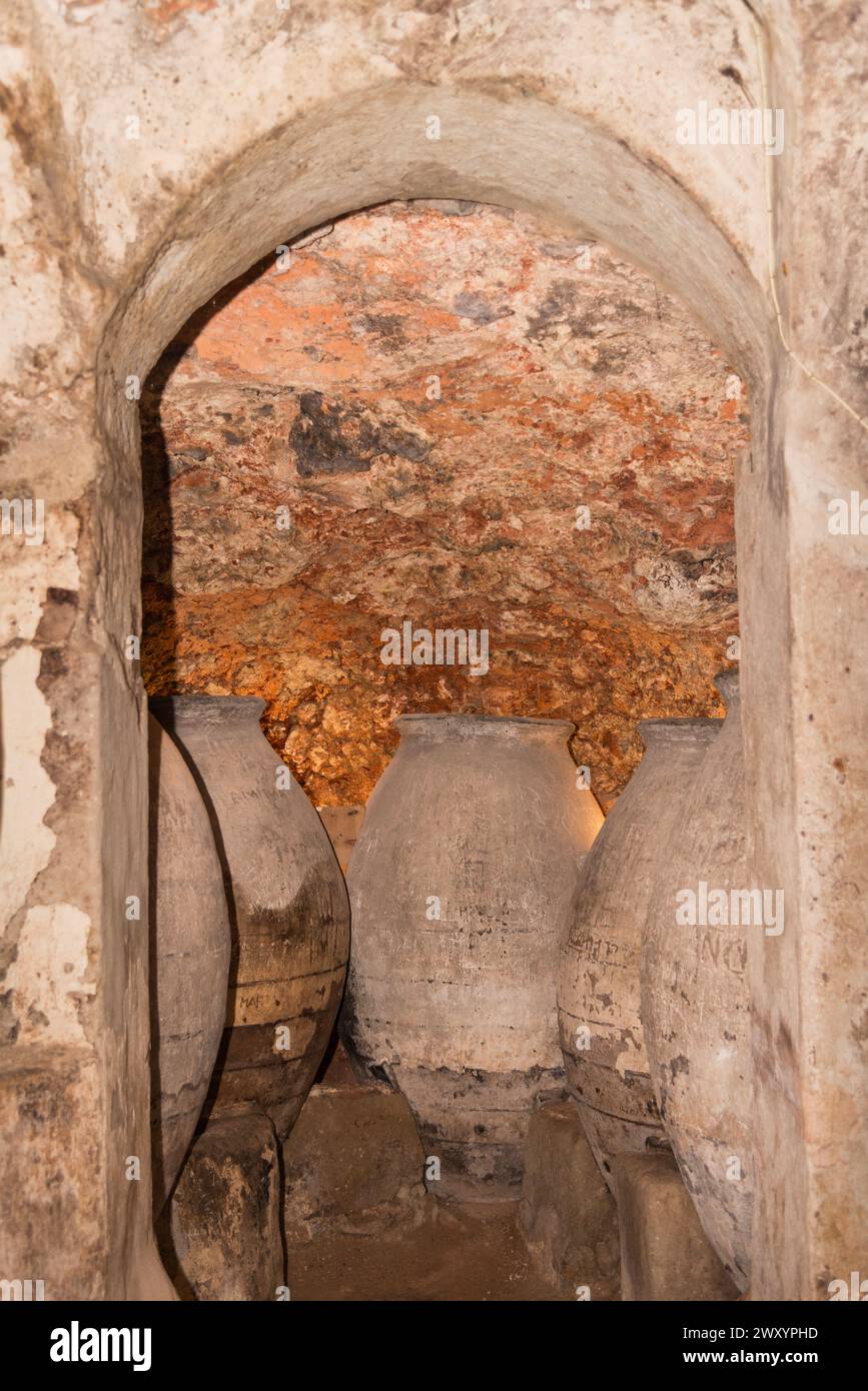 Time-worn clay pots for wine storage tucked into a rustic alcove within ...