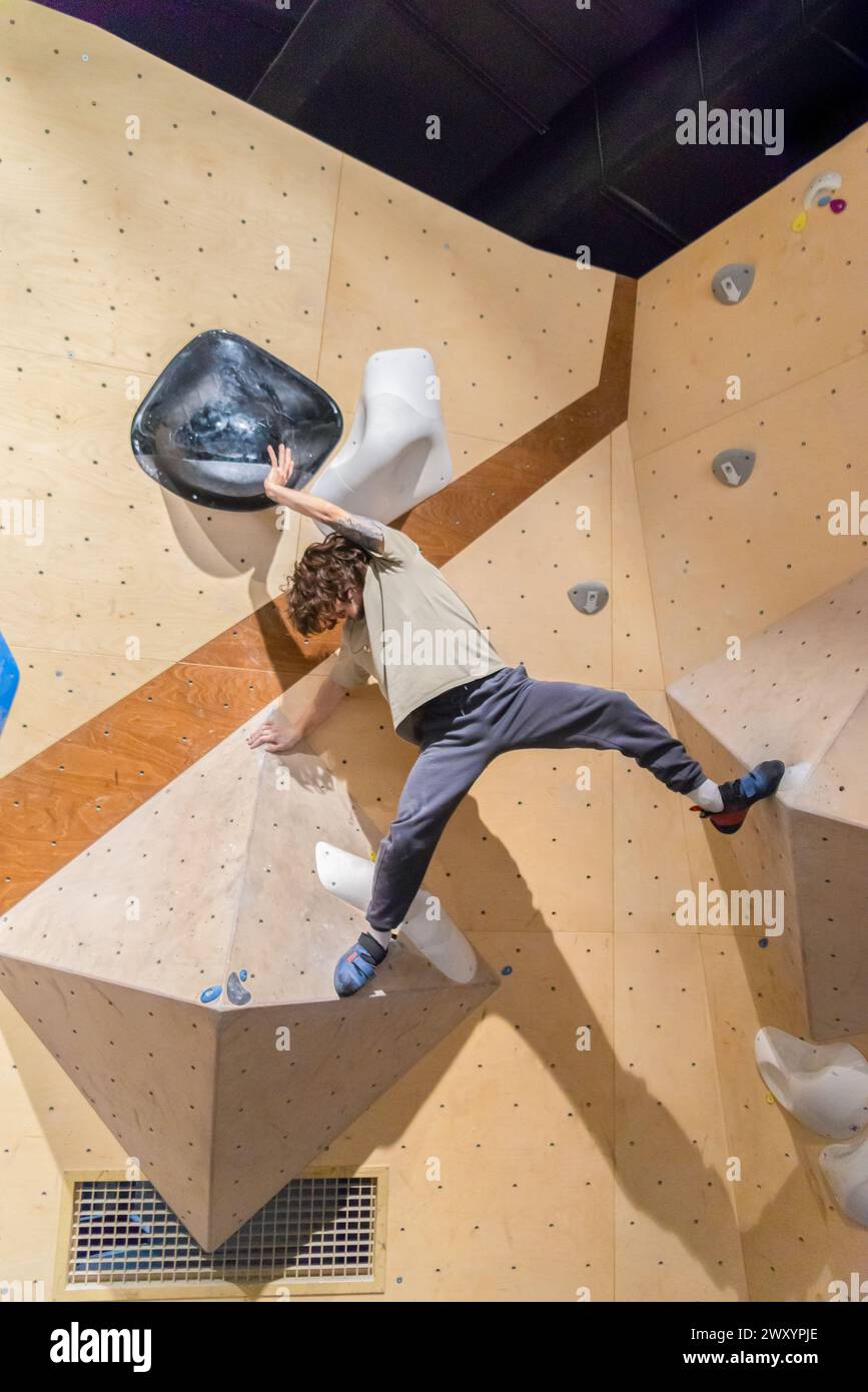 Climber in mid-action on an indoor bouldering wall, showcasing strength ...
