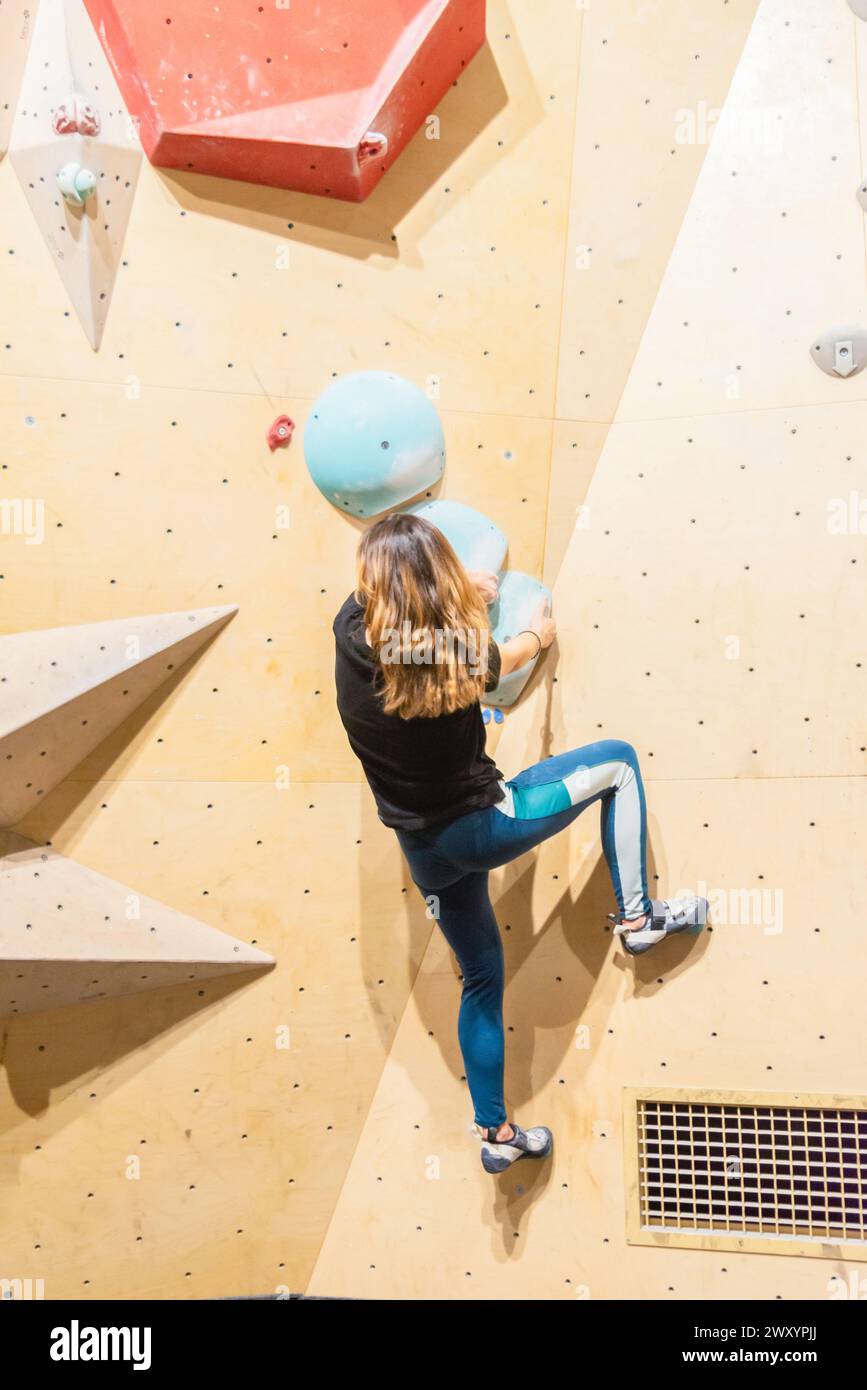 An overhead shot of a female climber scaling an indoor climbing wall ...