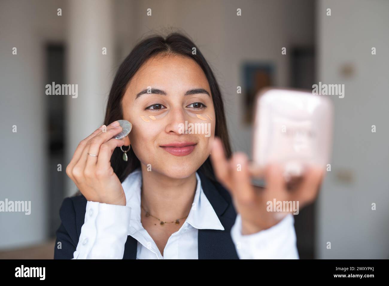 A businesswoman applies makeup before work, using a compact mirror and ...