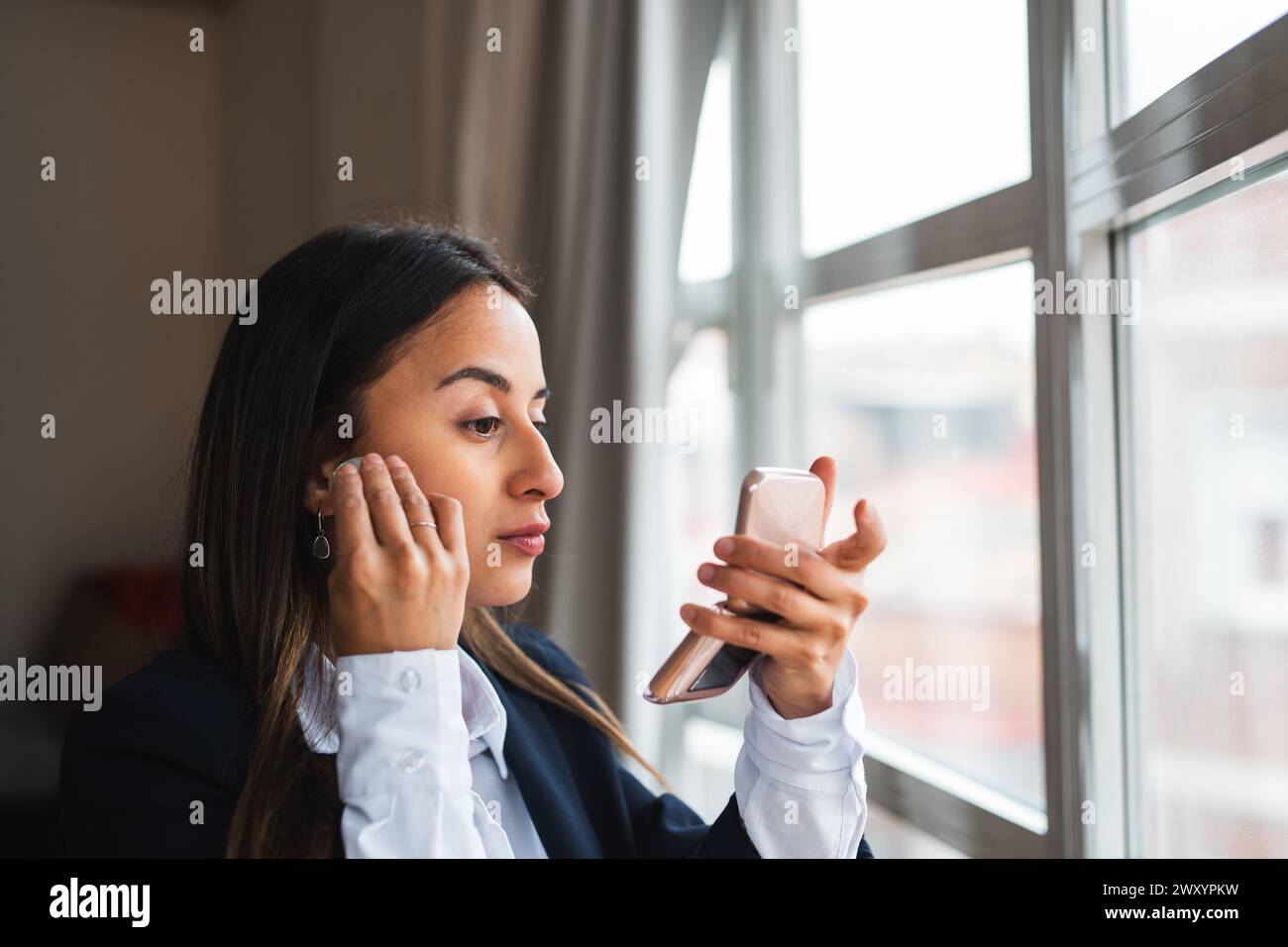 A businesswoman in a white shirt uses her mirror, checking her ...
