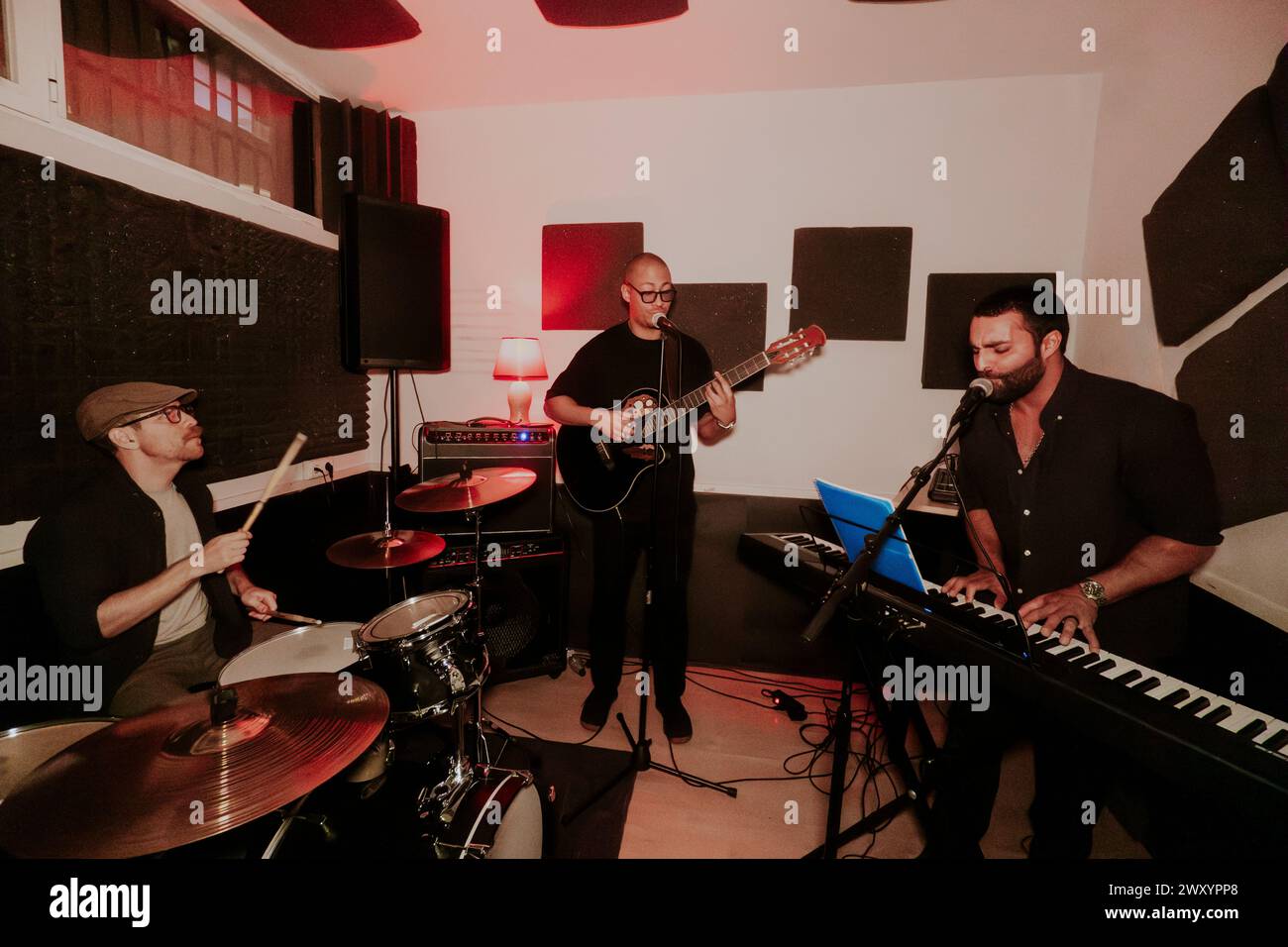 A male three-man music band plays in an intimate setting with a drummer ...