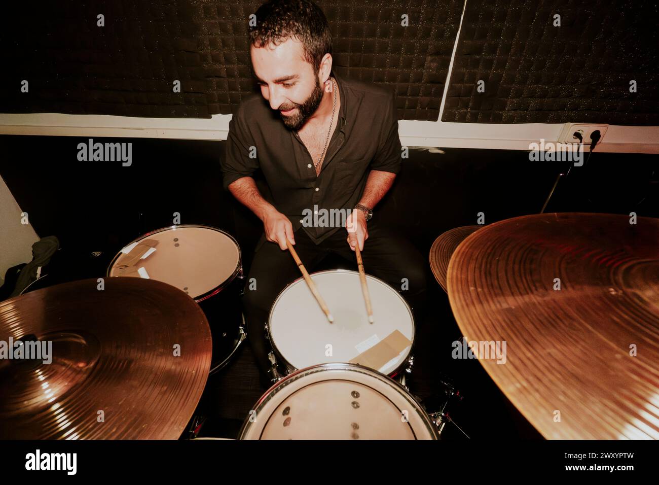 From above male drummer in black attire passionately playing a drum set ...