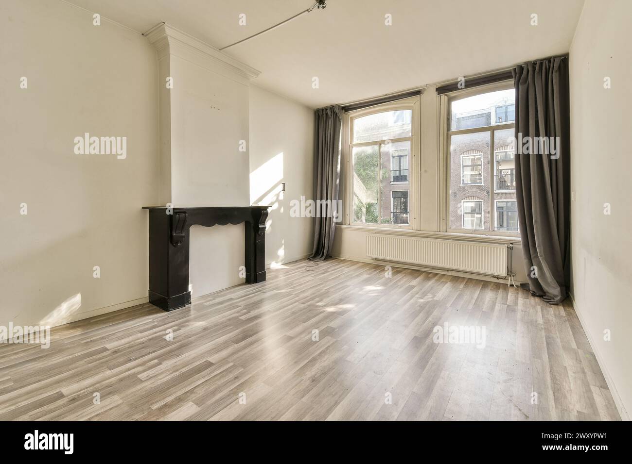 An empty, well-lit room featuring a classic black fireplace, large ...