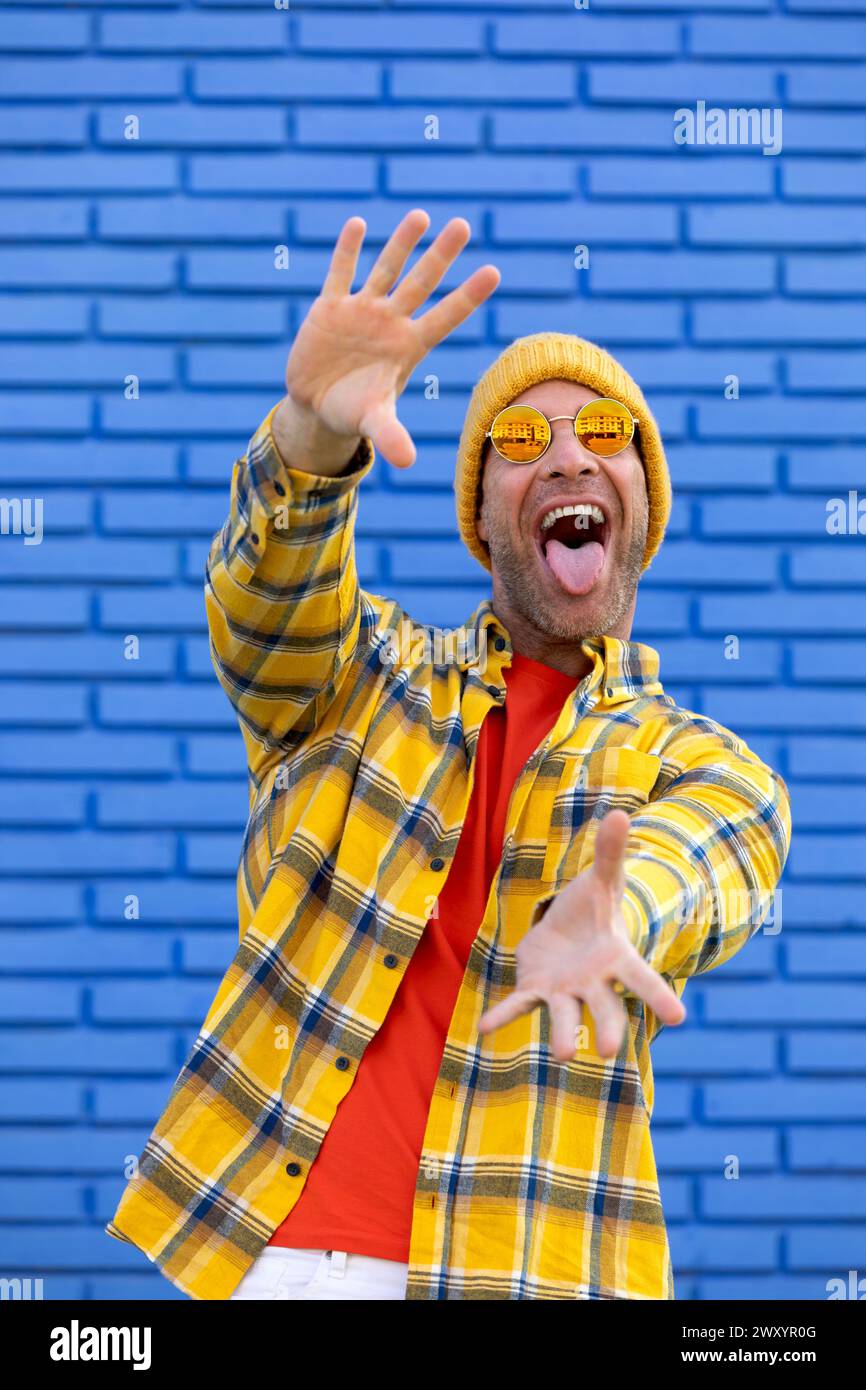 An ecstatic man in a yellow checkered shirt reaches out joyfully with a ...