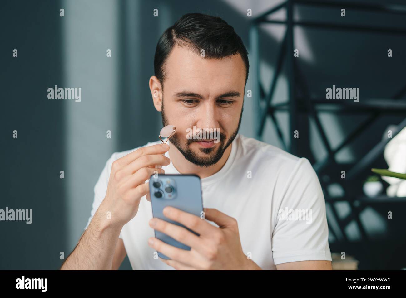 Man rolling face with jade stone roller for reducing puffiness ...