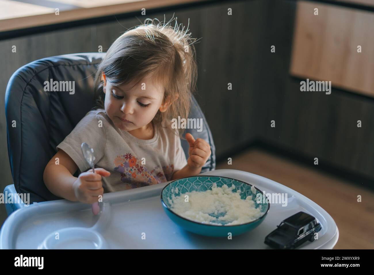 Cute little girl enjoying eating porridge for morning breakfast with ...