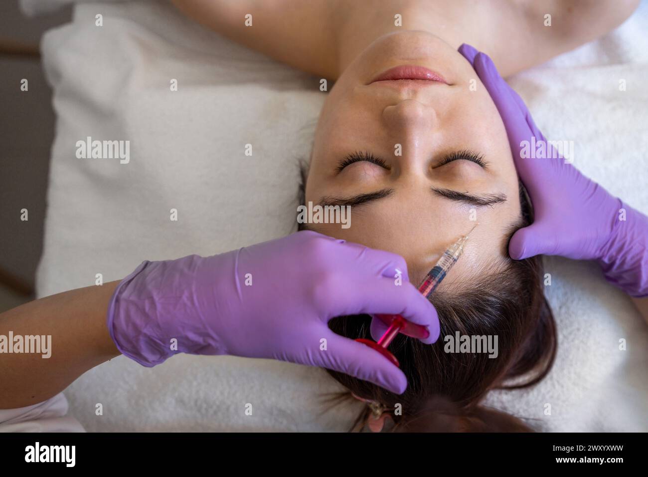 Beautiful woman receiving beauty injections in forehead with closed ...
