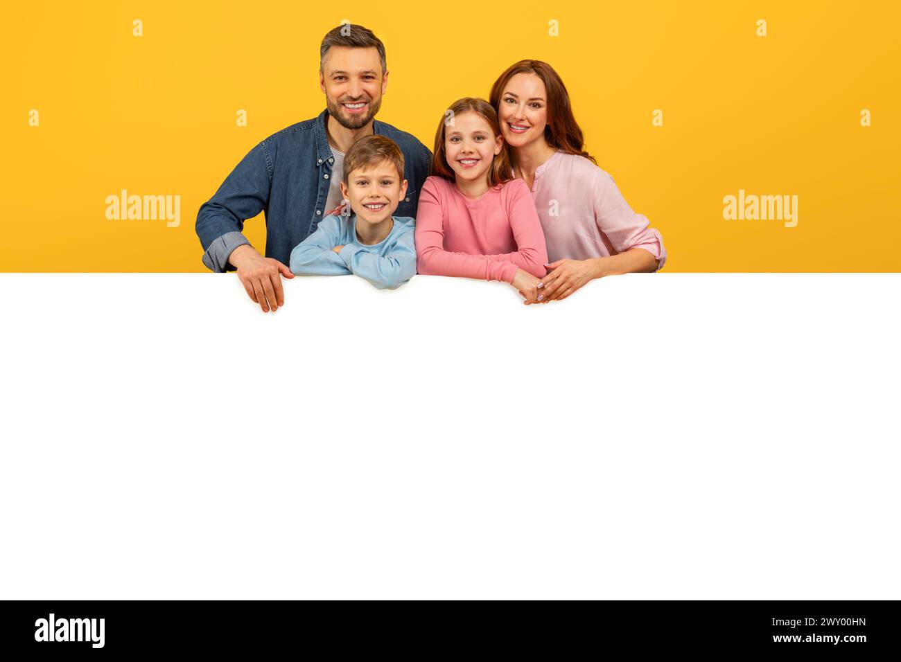 Happy family peeking over a white board Stock Photo - Alamy