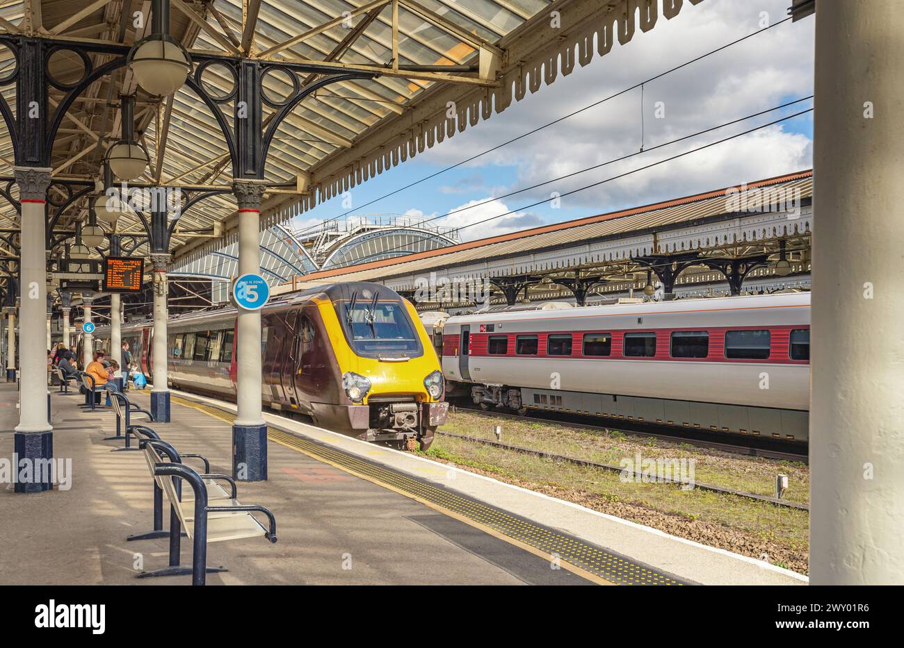 A train stands by a historic 19th Century canopy with columns. Metal ...