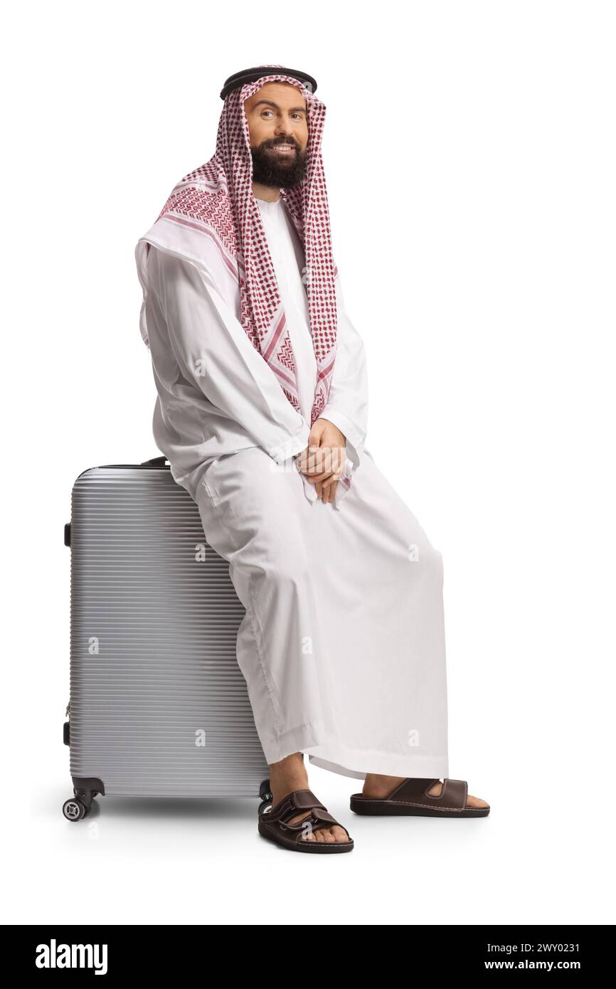 Saudi arab man sitting on a suitcase and looking at camera isolated on ...