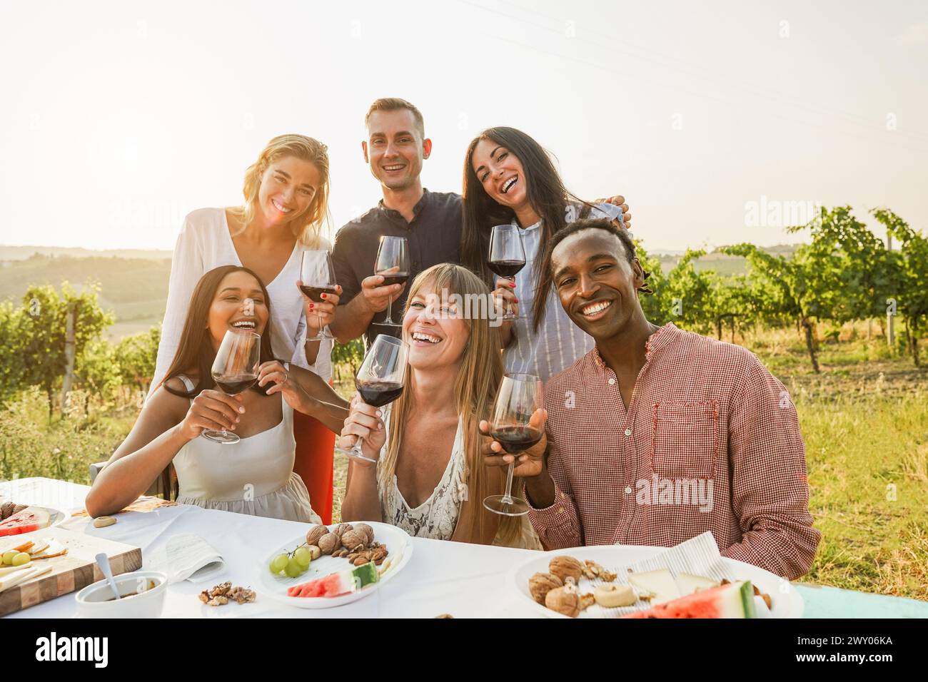 Happy adult friends having fun drinking red wine and eating together ...