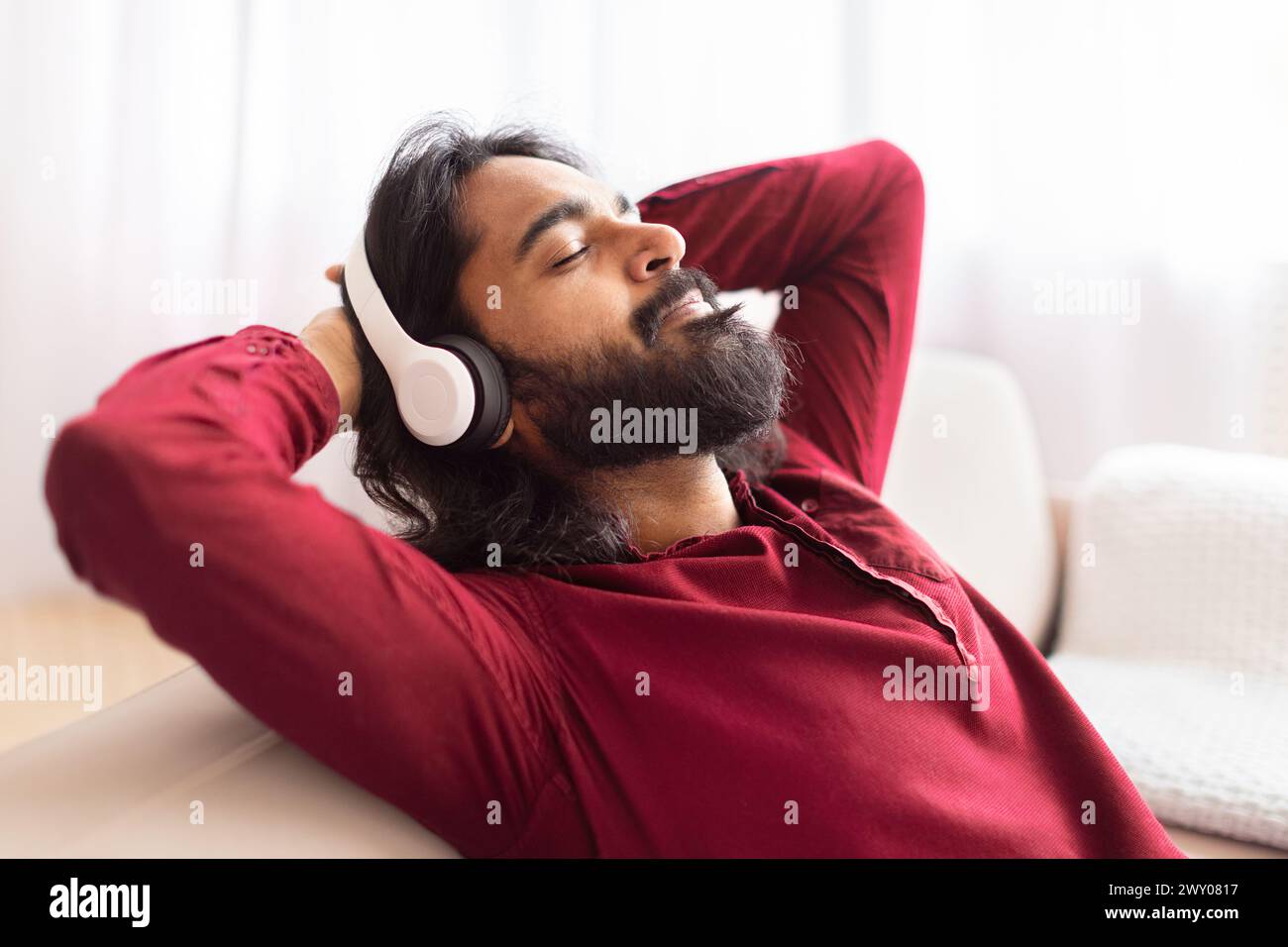 Man relaxing on couch at home, listening to music Stock Photo - Alamy