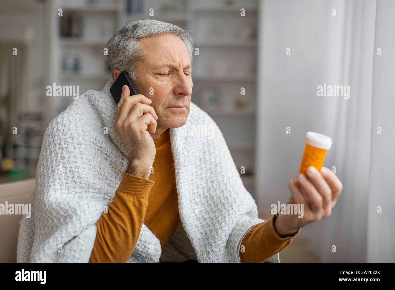 Senior examining medication while on a call Stock Photo - Alamy