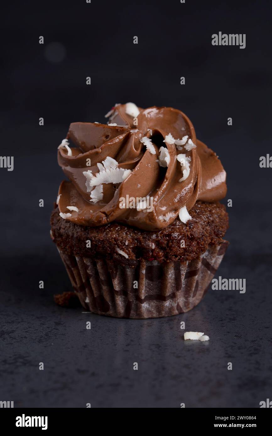 A luxurious chocolate cupcake topped with rich frosting and white chocolate shavings Stock Photo ...