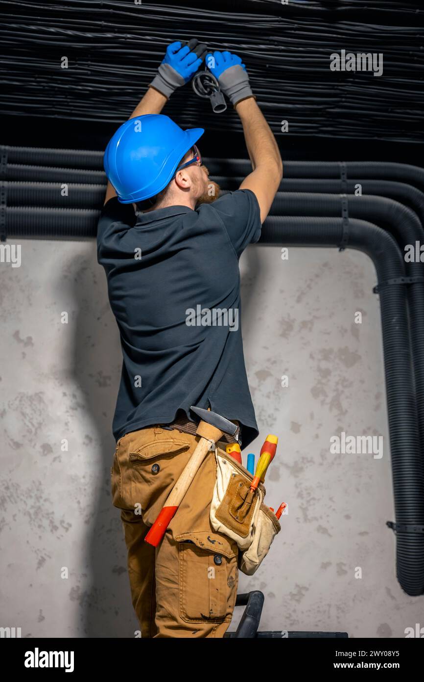 Electrician installing laying electrical cables on the ceiling inside ...