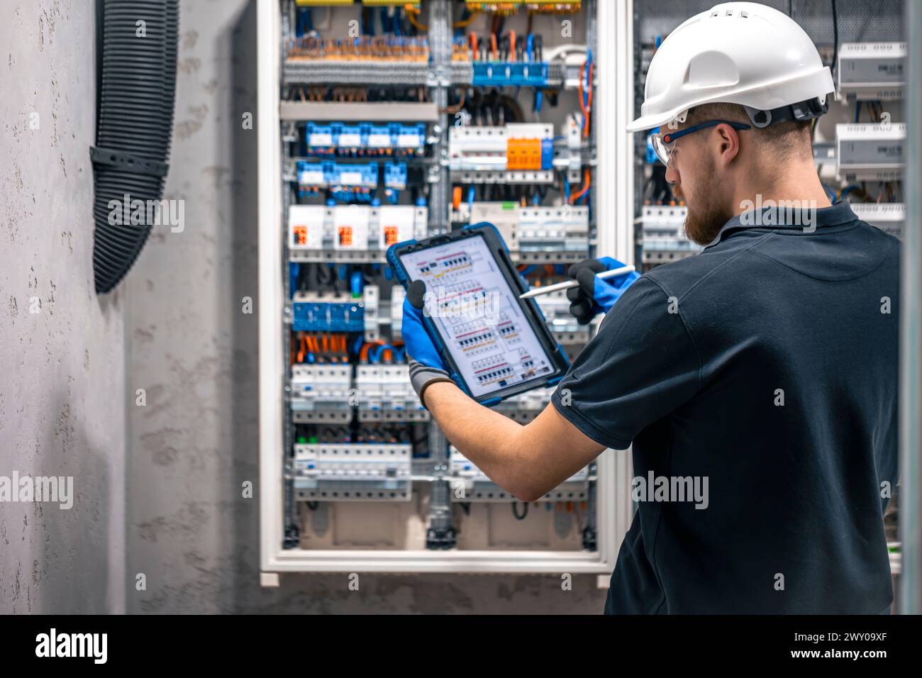 Electrician with tablet adjusting circuitry at junction box Stock Photo - Alamy