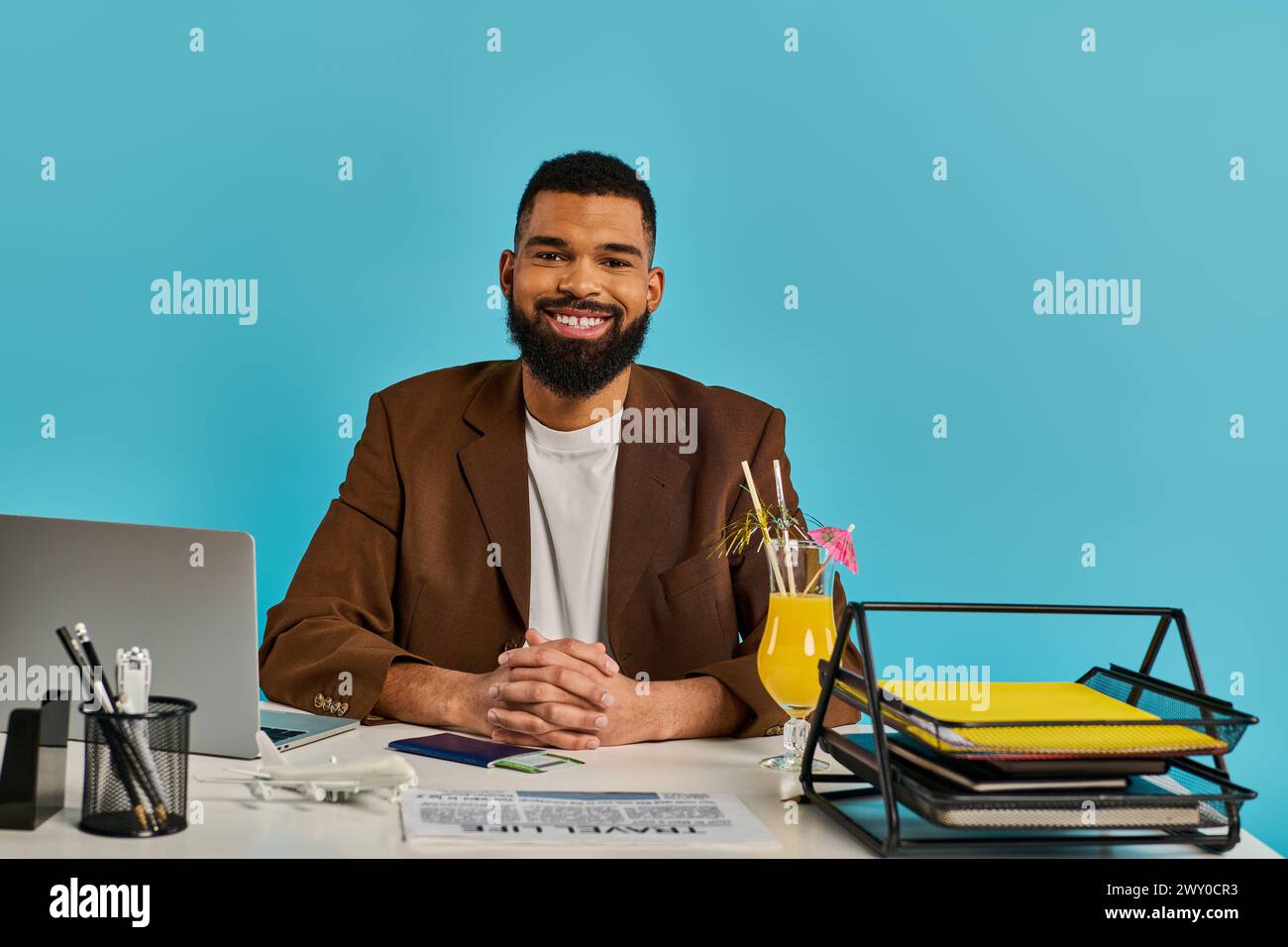 A man sits at a desk, focused on his laptop screen. His hands are ...