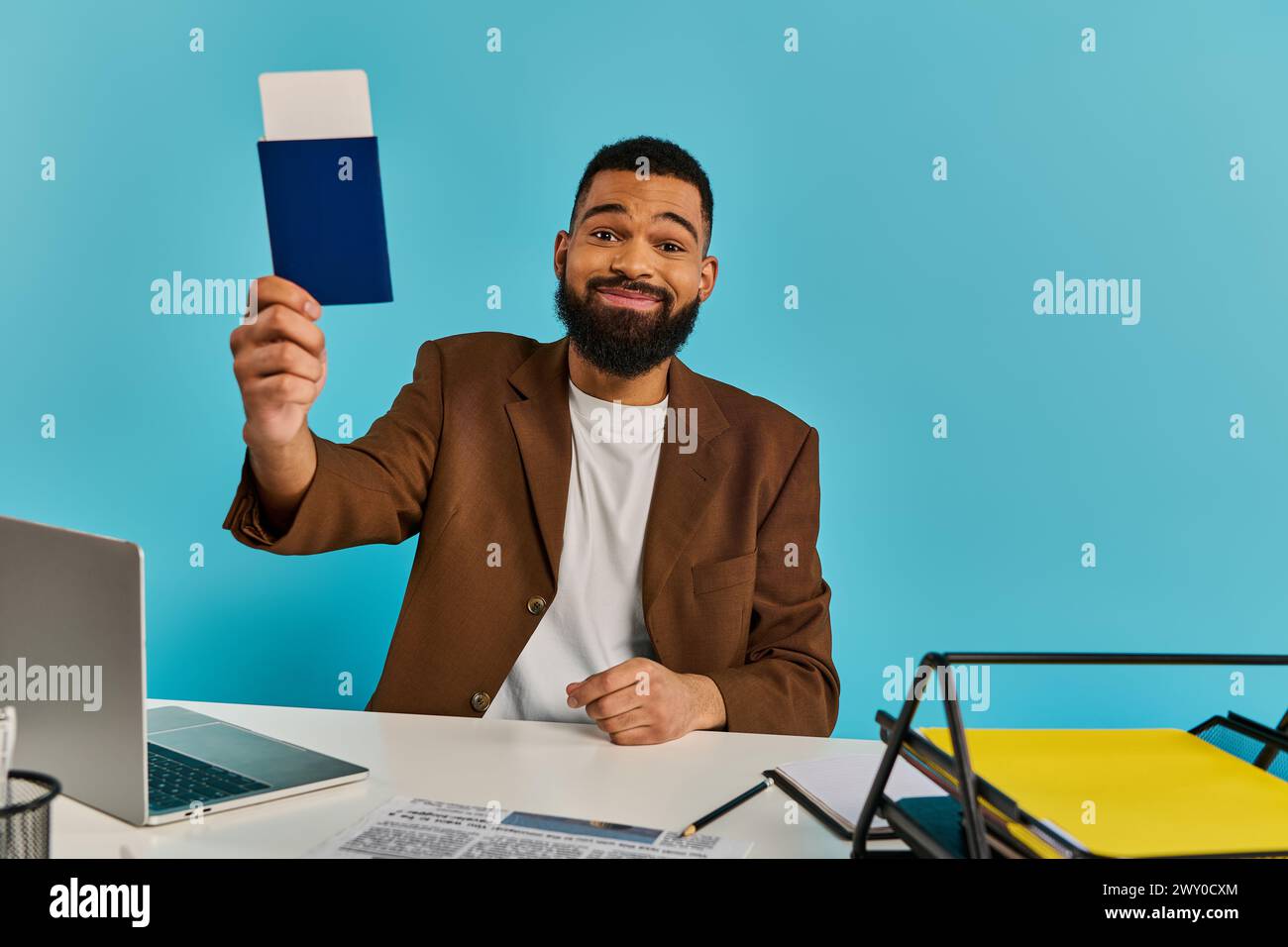 A man is seated at a desk, holding up a piece of paper in his hand ...