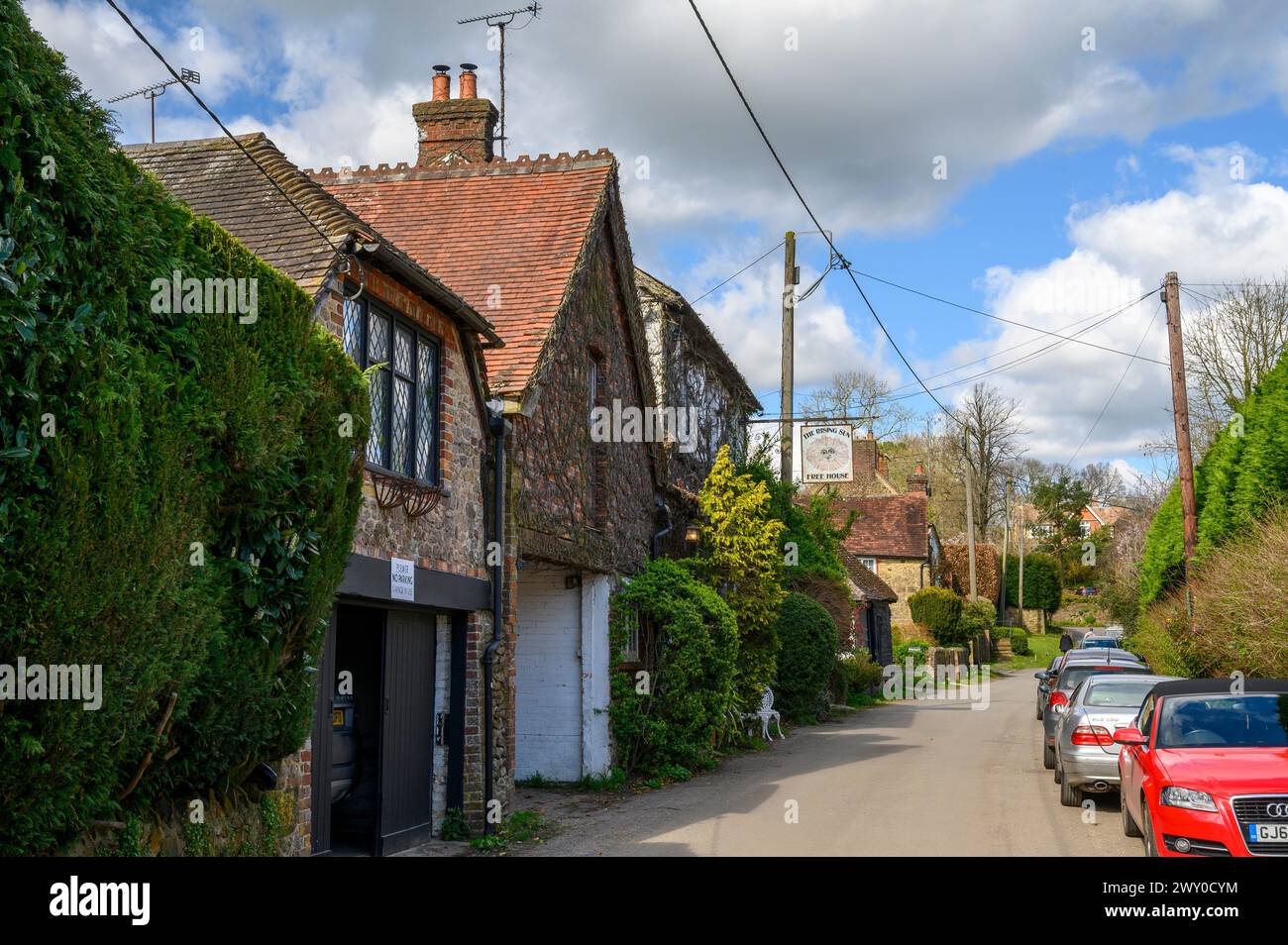 The front facade and sign of The Rising Sun, an old pub with cars ...