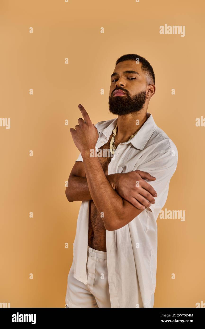 A man with a full beard stands confidently, arms crossed tightly across ...