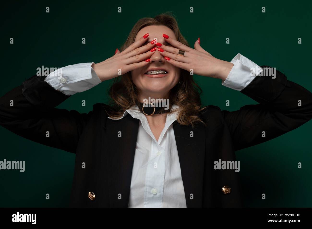 A woman with long hair covering her eyes with her hands, blocking out ...