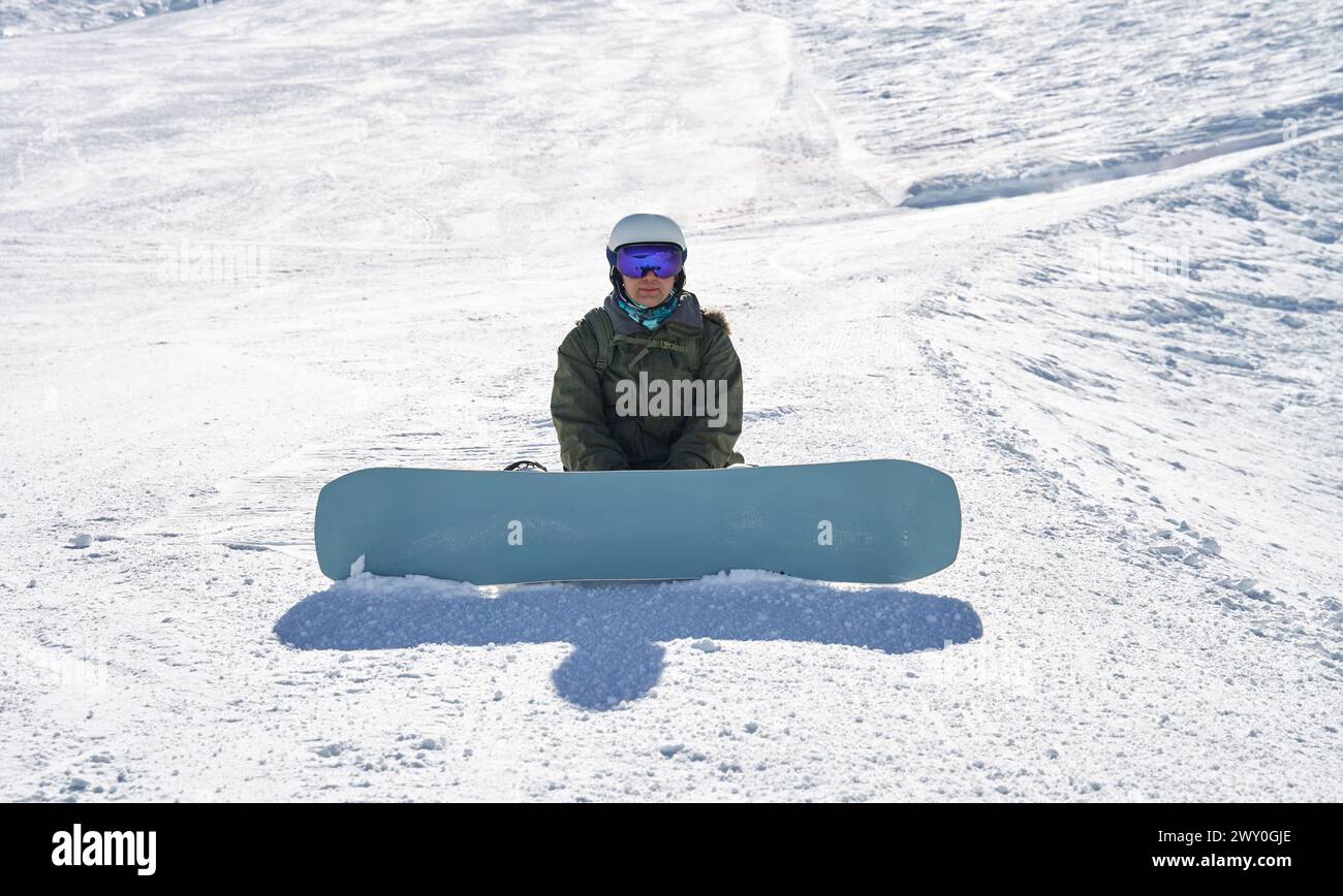 Front view of a snowboarder sitting in the snow, gazing forward on a ...