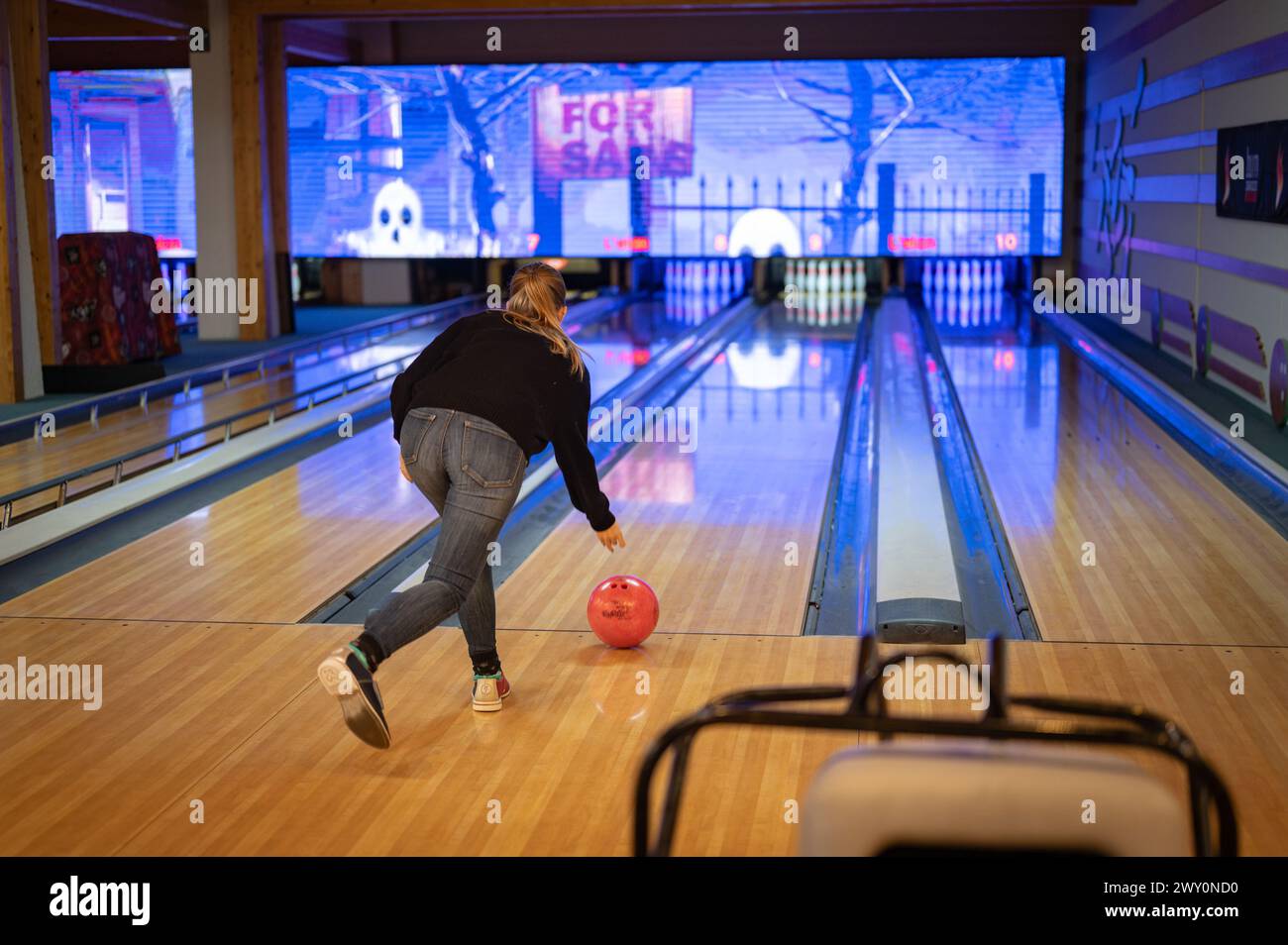 Rear view of a girl throwing the bowling ball. Throwing with technique ...