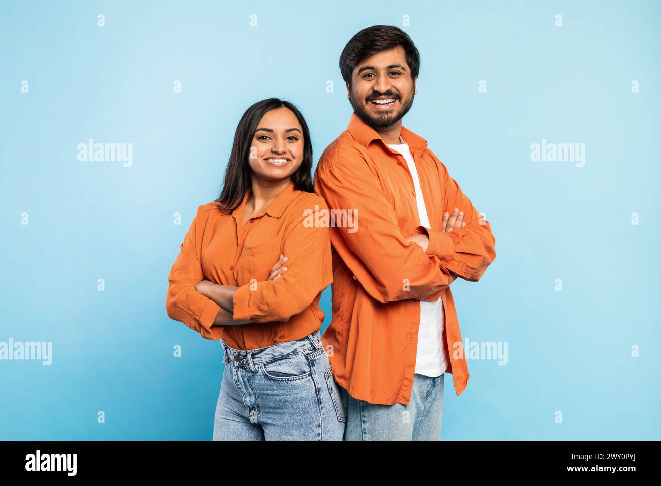 Two people posing confidently together on blue Stock Photo - Alamy