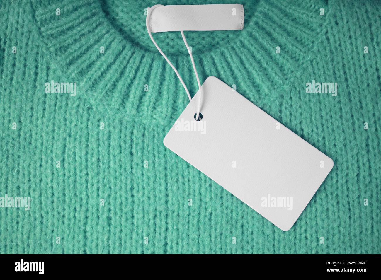 Blank clothing tag and inner label on neck of green knitted sweater ...
