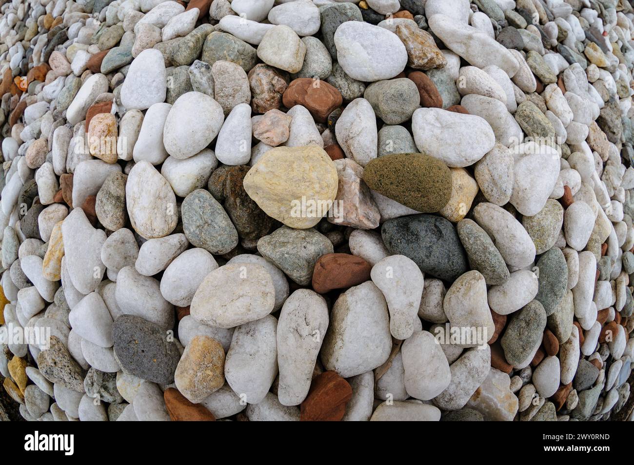 An assortment of rounded pebbles in various colors forms a spiral ...