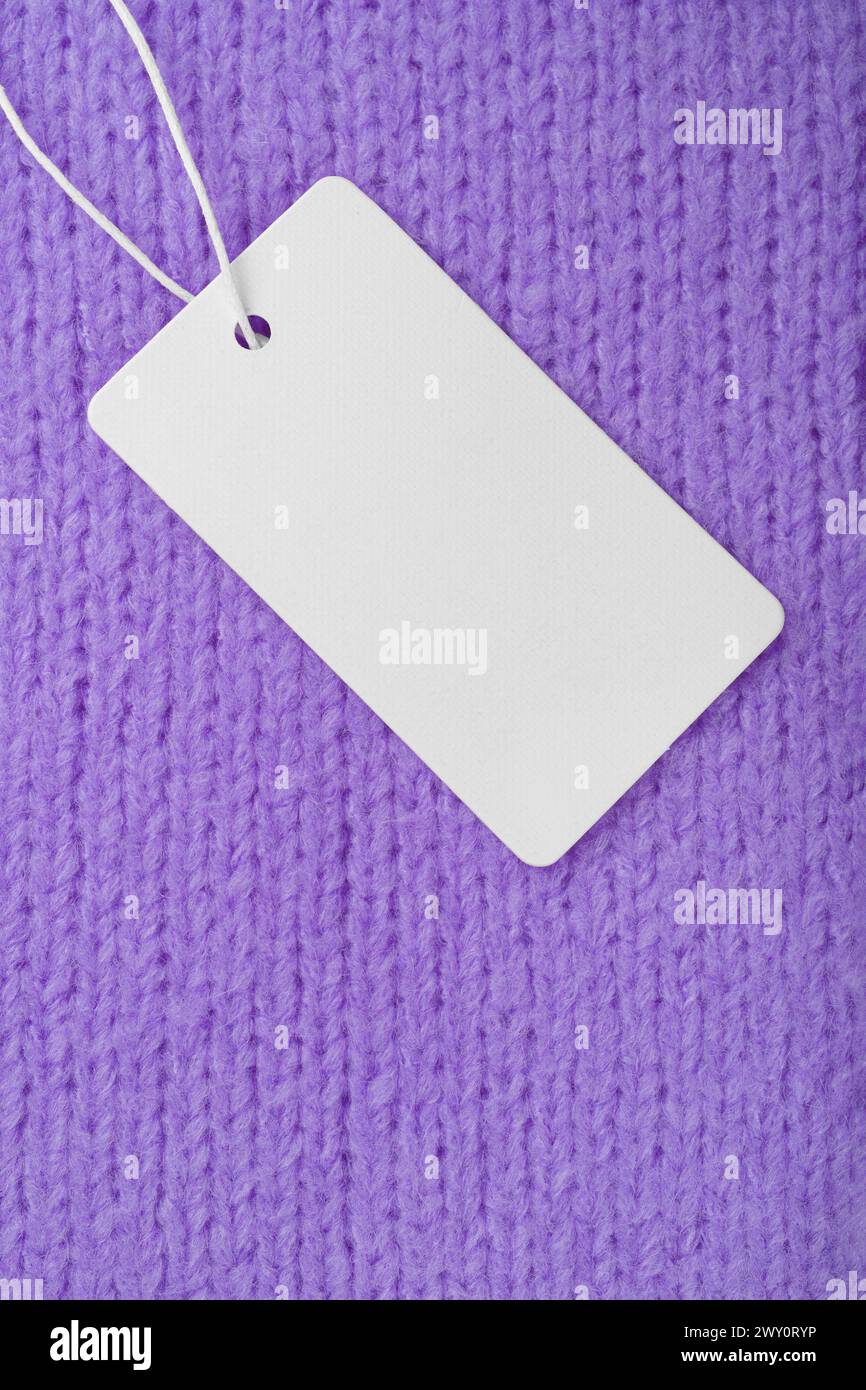 Blank clothing label on purple knitted sweater background. Mockup ...