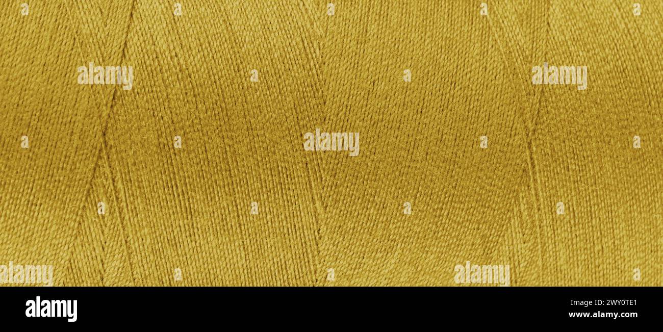 Texture of yellow color threads in spool close up, macro. Wide banner ...